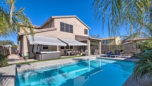 Uma casa com piscina, móveis de pátio e área de estar coberta ao ar livre.