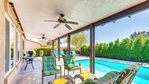 Uma área externa coberta com piscina, espreguiçadeiras e ventilador de teto.