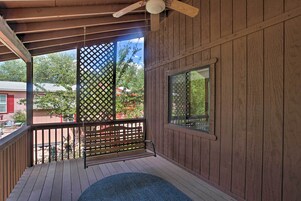 Um deck de madeira com ventilador de teto, tela de treliça e vista para uma área residencial.