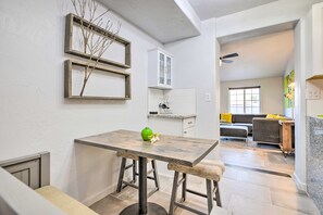 Uma cozinha moderna com uma mesa de madeira, armários brancos e vista para a sala de estar.