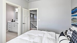 Quarto com cama, paredes brancas, um quadro e uma escada.