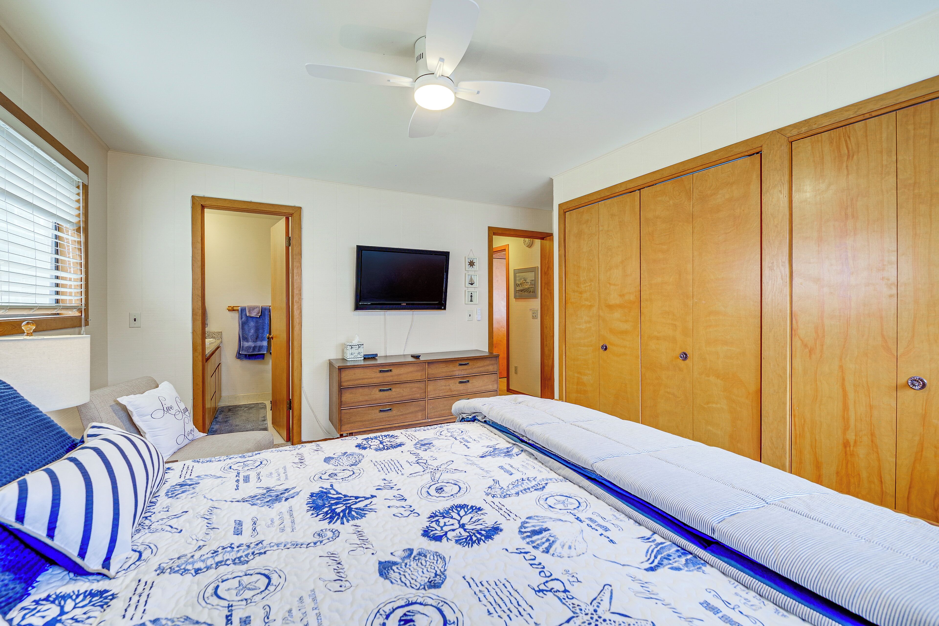 Quarto com cama, cômoda, televisão e guarda-roupa.
