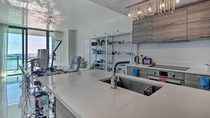 Cozinha moderna com uma ilha grande, eletrodomésticos embutidos e vista para a cidade.