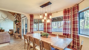 Uma sala de jantar espaçosa com uma grande mesa de madeira e cadeiras, com cortinas xadrez e uma parede de pedra.