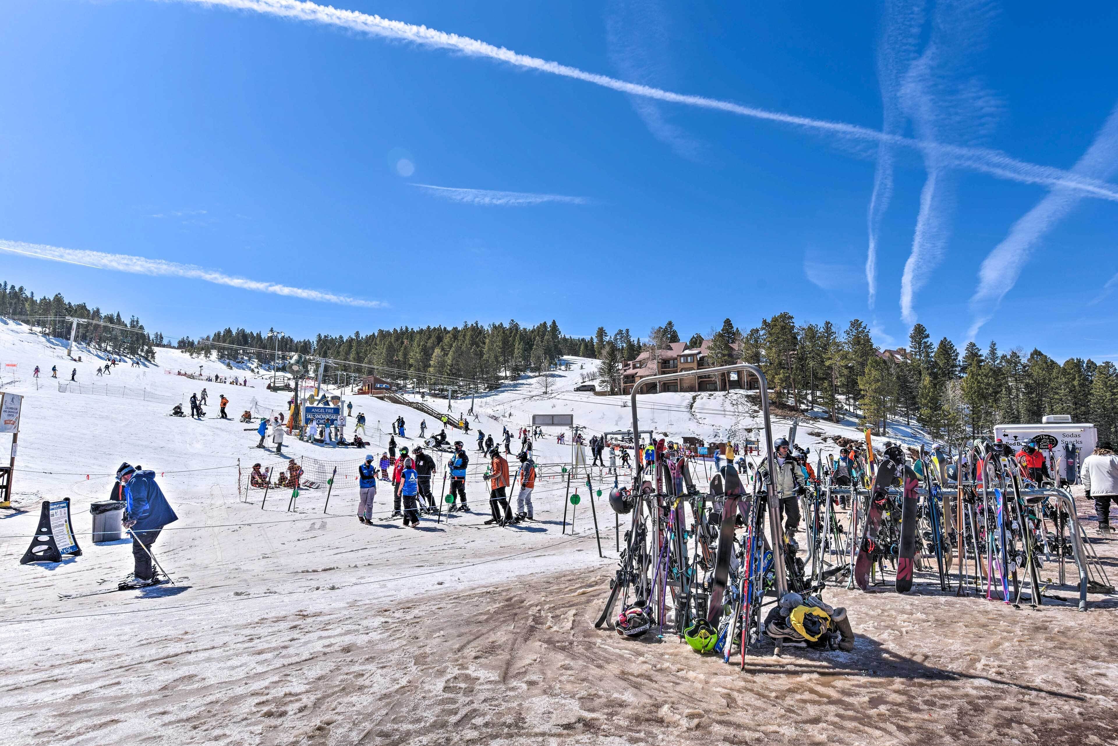Uma estância de esqui com um teleférico, encostas cobertas de neve e um céu azul límpido.