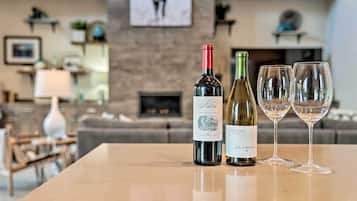 Mesa com duas garrafas de vinho e dois copos de vinho numa sala de estar moderna.
