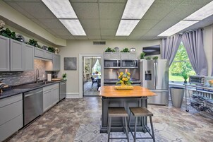 Uma cozinha moderna com armários cinza, eletrodomésticos de aço inoxidável e uma ilha central com banquetas.