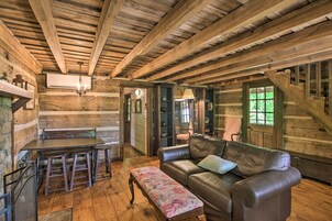 Interior rústico de cabana com mesa de jantar de madeira, sofá de couro e um banco.