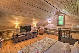 Um quarto aconchegante com paredes de madeira, uma cama com roupa de cama florida, uma TV e duas luminárias.