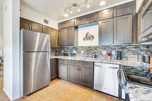 Uma cozinha moderna com eletrodomésticos de aço inoxidável, armários de madeira escura e painel de backsplash revestido.