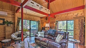 Interior acolhedor de uma cabana com um sofá de couro, uma poltrona de balanço e uma mesa de jantar.
