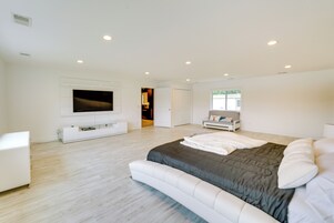 Quarto moderno com uma cama grande, TV na parede e design minimalista.