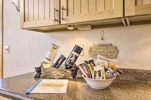 Uma bancada de cozinha com garrafas de vinho, uma tigela de petiscos e um letreiro de boas-vindas.