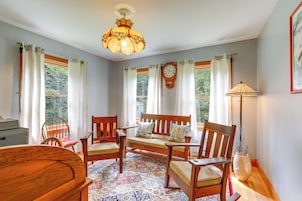 Um quarto aconchegante com um banco de madeira, cadeiras, uma escrivaninha e uma luminária.