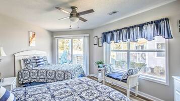 Quarto com duas camas, um ventilador de teto e uma janela com vista para o quintal.