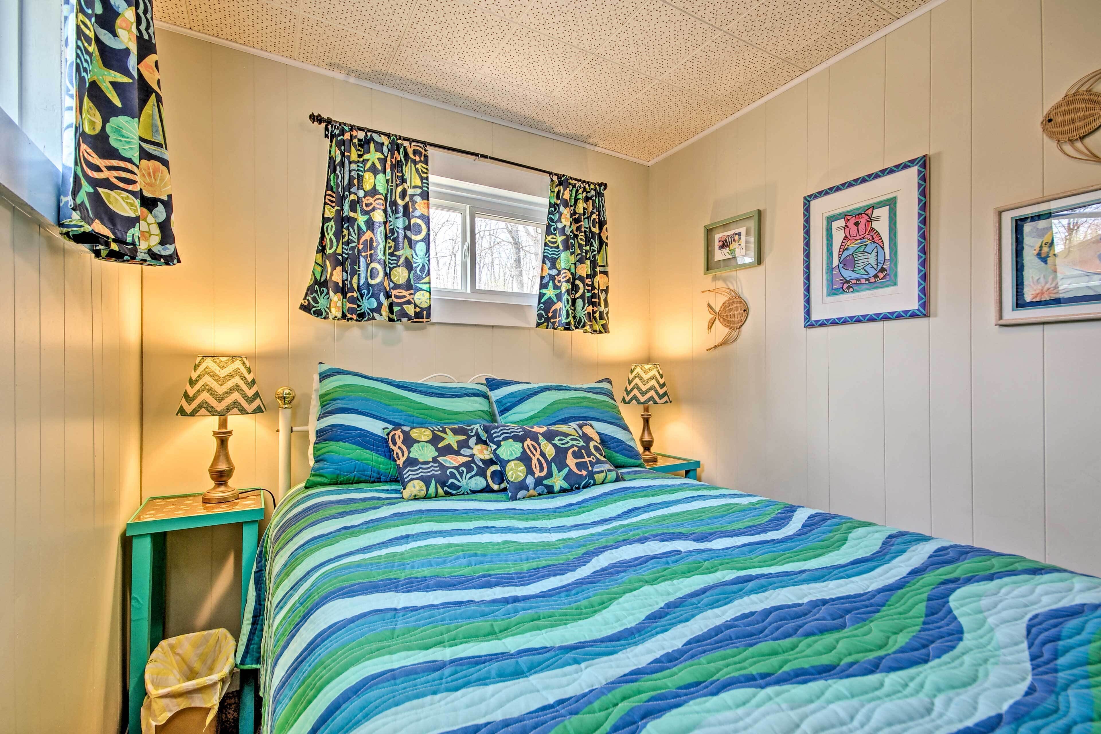 Quarto com cama, cortinas, obras de arte na parede e uma janela.