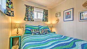 Quarto com cama, cortinas, obras de arte na parede e uma janela.