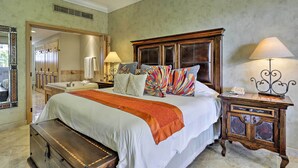 Quarto bem arrumado com cama grande, mesas de cabeceira, um banco, espelho e guarda-roupa.