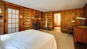 Quarto estilo cabana de madeira com uma cama, lareira, escrivaninha e uma cadeira.