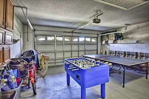 Uma garagem com mesa de futebol de mesa, mesa de tênis de mesa e uma bicicleta.