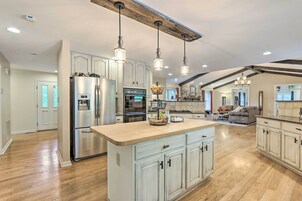 Uma cozinha ampla com ilha central, eletrodomésticos de aço inoxidável e iluminação pendente.