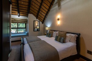 Quarto com cama grande, um assento junto à janela e vista para o verde lá fora.