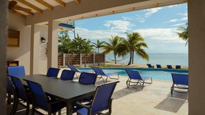 Uma área externa coberta com piscina, espreguiçadeiras e uma mesa com cadeiras.