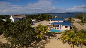 Uma propriedade à beira-mar com piscina, palmeiras e vista para o mar.