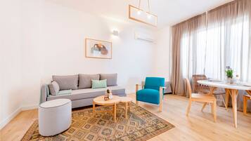 Uma sala de estar moderna com um sofá, uma mesa redonda, uma poltrona azul e um tapete estampado.