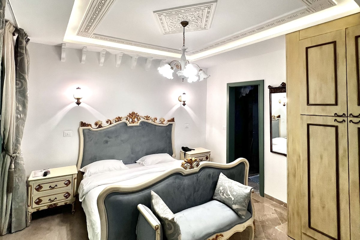Quarto com cama grande, mesa de cabeceira, penteadeira e guarda-roupa.
