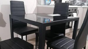 Uma cozinha moderna com mesa de jantar de vidro e cadeiras pretas.