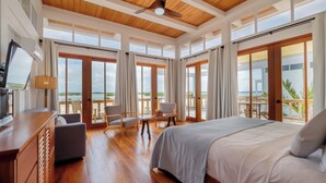 Quarto amplo com cama grande, escrivaninha e cadeira, com janelas espaçosas e varanda.
