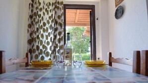 Uma mesa de jantar com toalha de mosaico, dois pratos amarelos, uma garrafa e um copo.