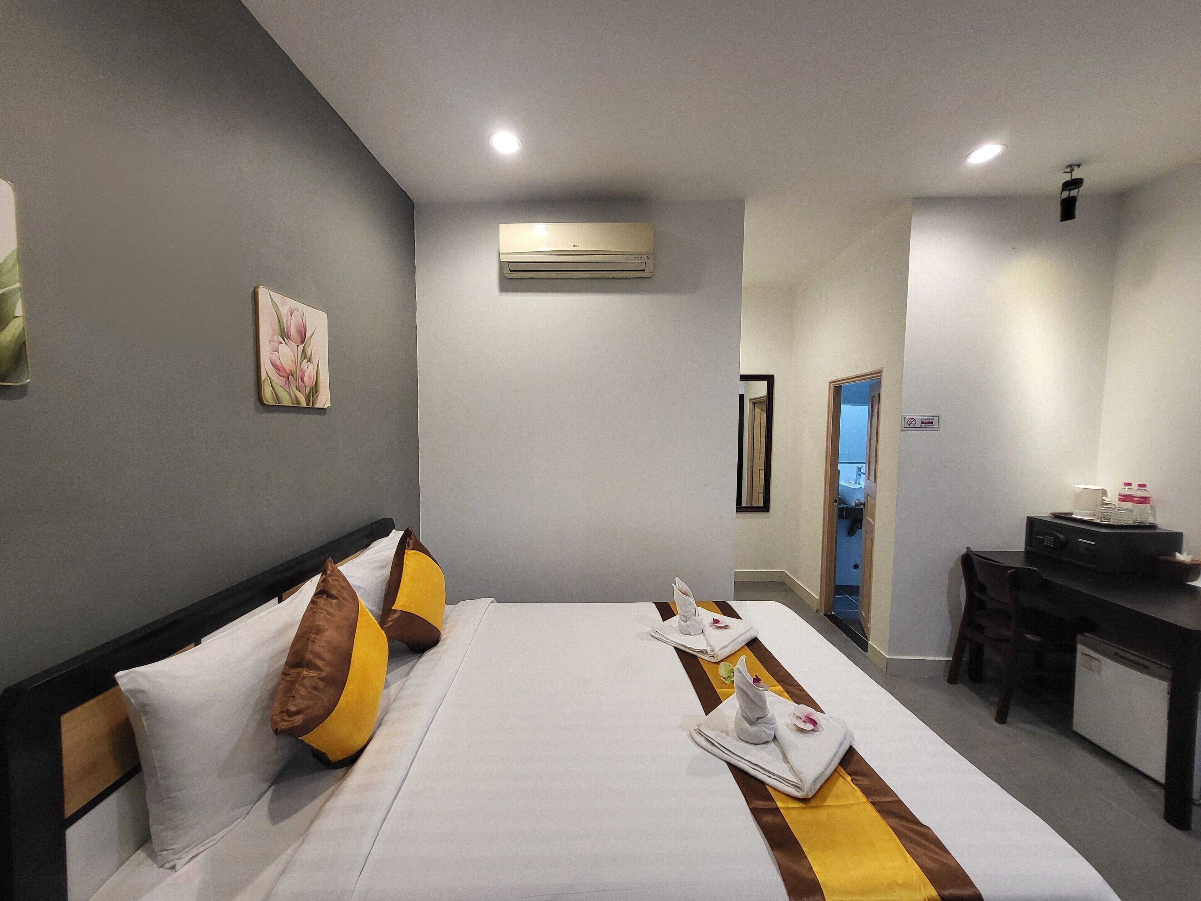 Quarto de hotel com cama, almofadas, escrivaninha e espelho.