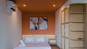 Quarto de hotel moderno com cama, sofá, uma pequena mesa e armário embutido.