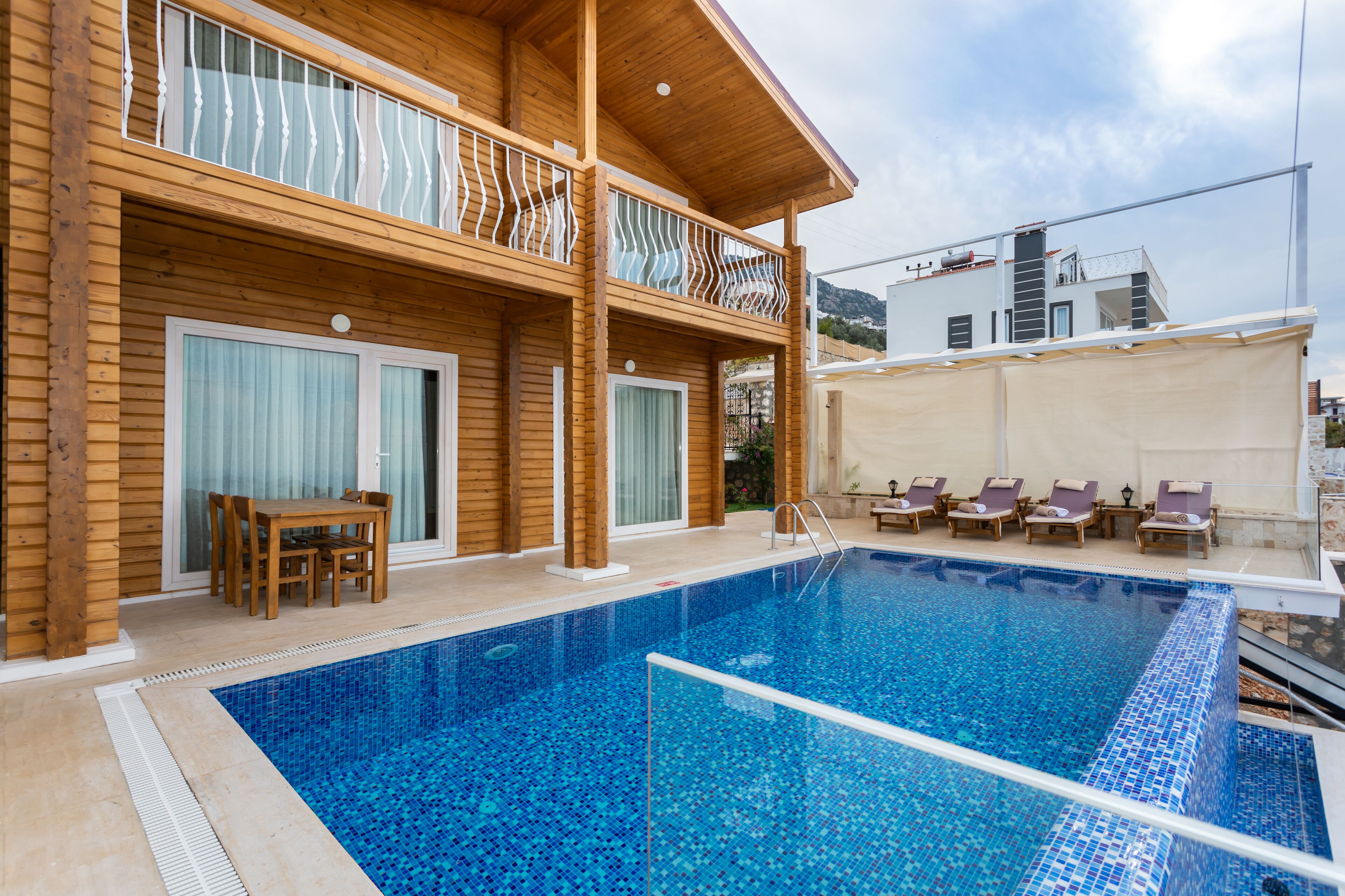 Um edifício de madeira com piscina e área de estar externa.