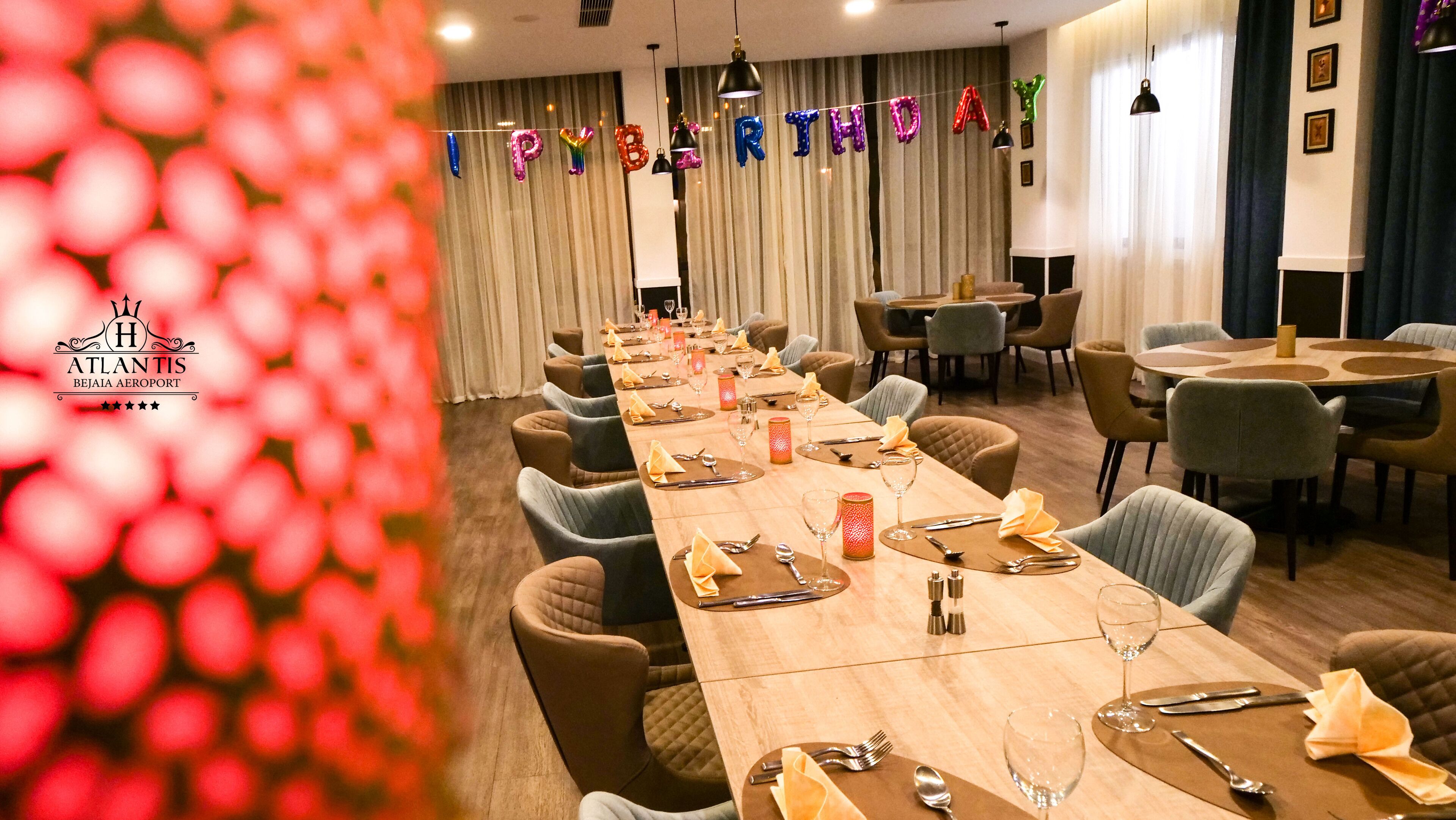 Uma sala de banquetes com longas mesas preparadas para uma celebração, com um banner 'PARTY' e sinalização 'BEIJIA AEROPORT'.