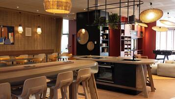 Uma cozinha moderna com ilha central, banquetas, iluminação pendente e uma estante.
