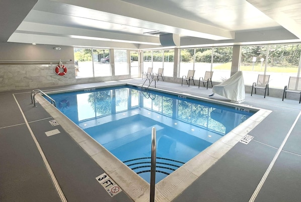 Piscina interna com água cristalina, boia salva-vidas e espreguiçadeiras.