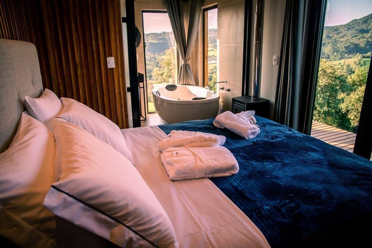 Quarto com uma cama grande, banheira e vista para o exterior.