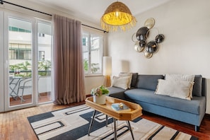 Uma sala de estar moderna com sofá, mesa de centro, um objeto decorativo na parede e vista para o exterior.