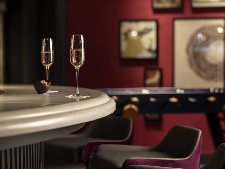 Uma área de bar com duas taças de champanhe, uma pequena tigela e uma mesa com cadeiras.