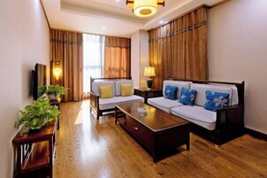 Sala de estar com sofá, mesa de centro, televisão e cortinas.