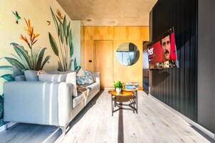 Uma sala de estar moderna com um sofá, uma mesa de centro e uma TV fixada na parede.