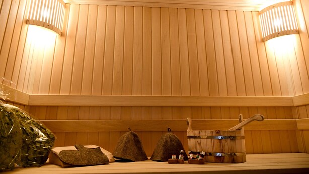 Uma sauna de madeira com bancos e um balde contendo uma concha.