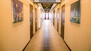 Um corredor de hotel com portas em ambos os lados, cada uma com uma pintura de paisagem urbana.