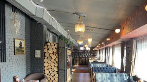 Um restaurante com um balcão comprido, cabines forradas em azul e carpete estampado.