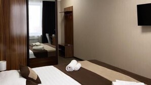 Quarto de hotel com uma cama grande, guarda-roupa, espelho e televisão de ecrã plano na parede.