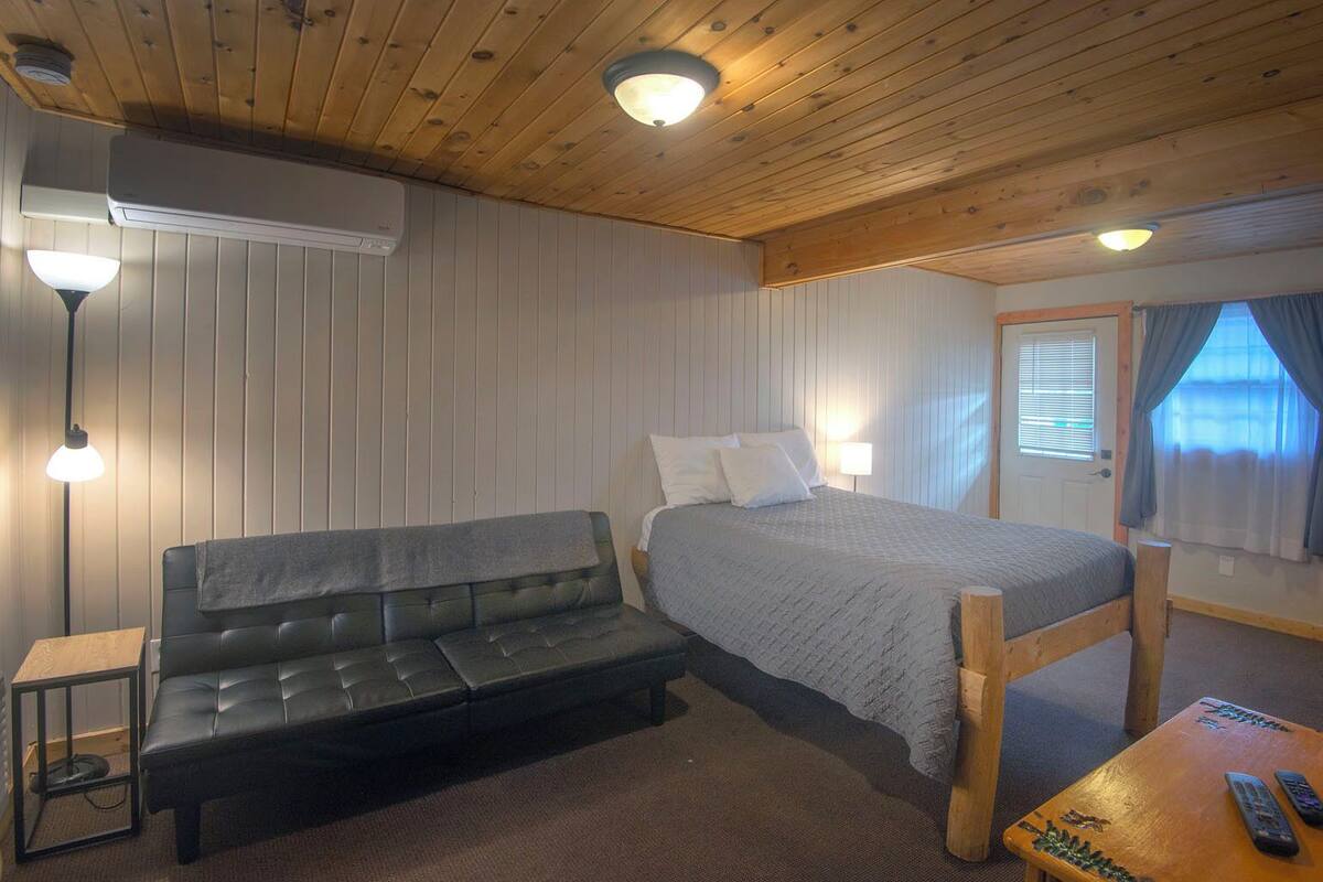 Um quarto acolhedor com uma cama, um sofá, uma mesa pequena e um abajur.
