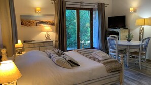 Quarto com cama, luminárias de cabeceira, escrivaninha com cadeira, televisão e janela com cortinas.